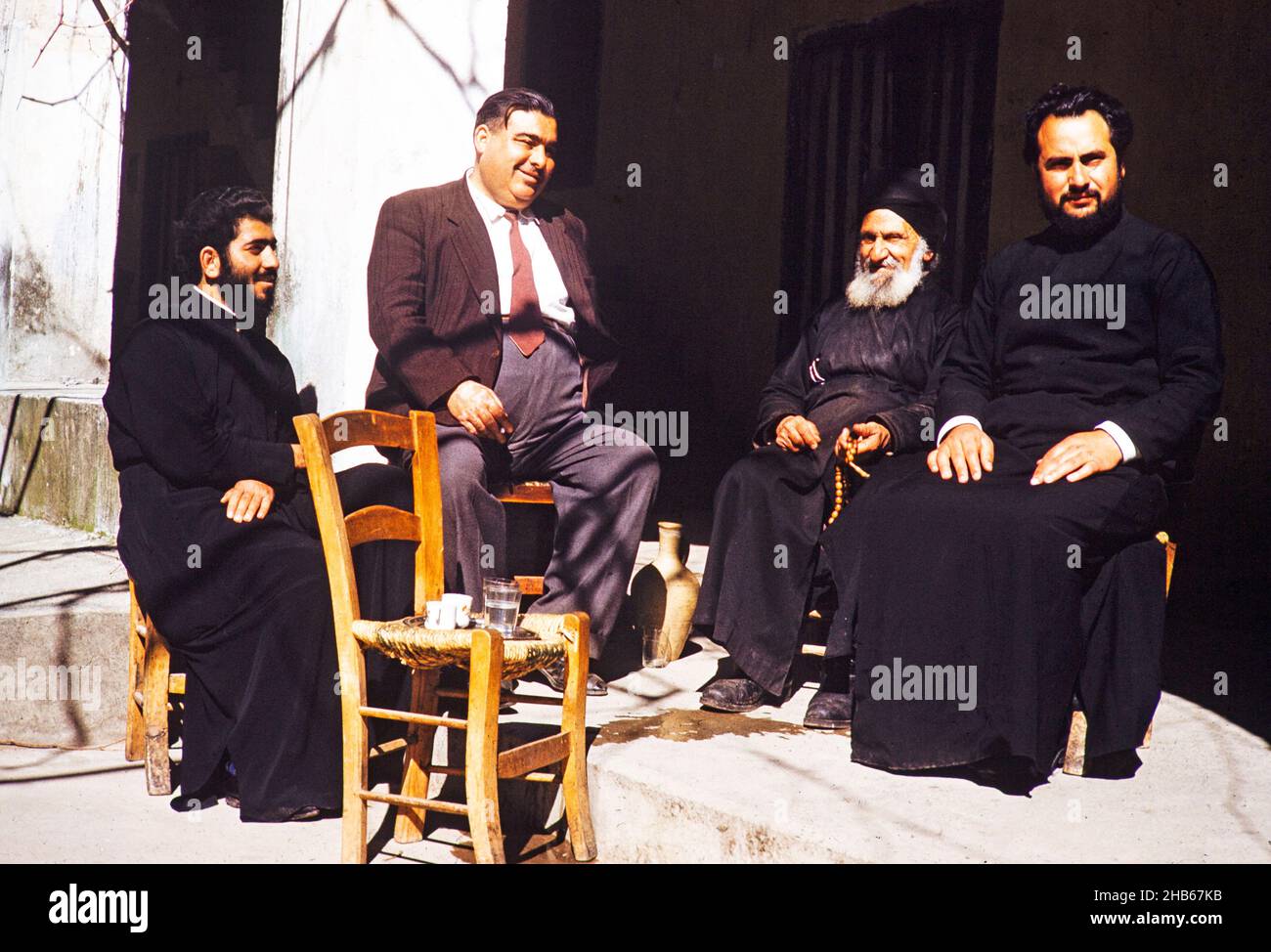 Monks sitting with another man outside Panagia Machairas Monastery ...