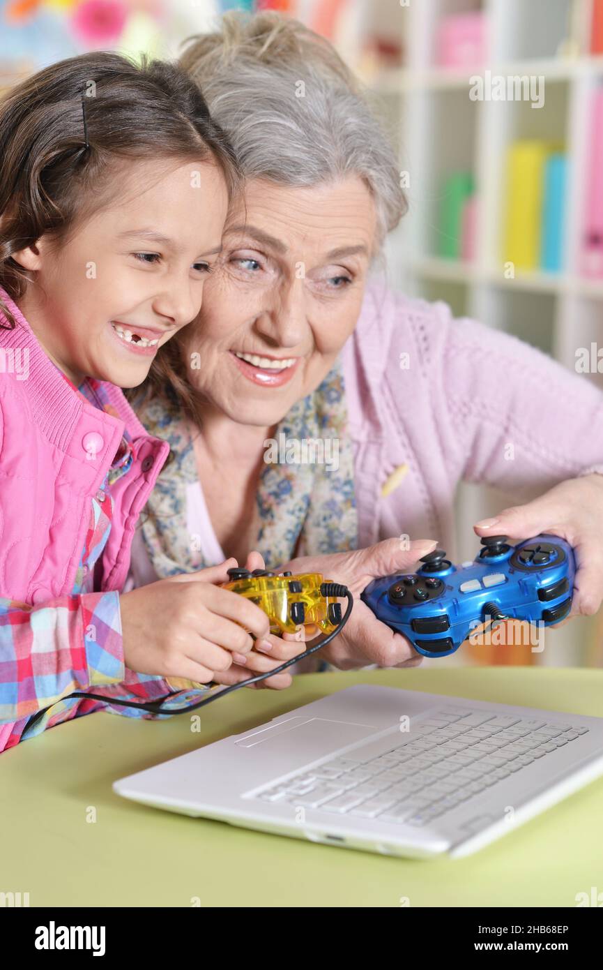 Granny with her granddaughter playing computer game on laptop Stock ...