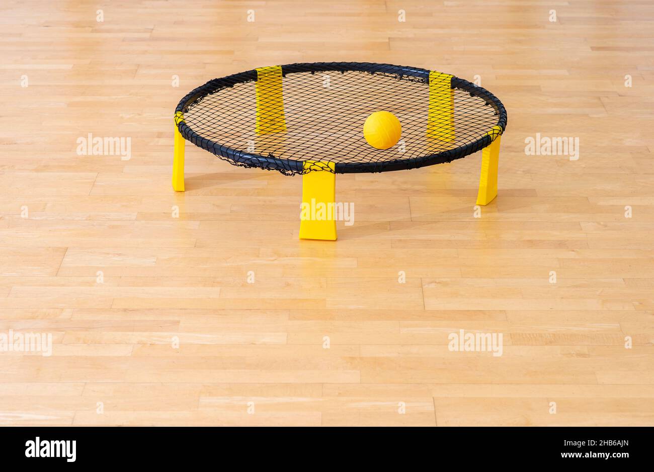 Spike ball game with yellow ball on hardwood court floor. Horizontal ...