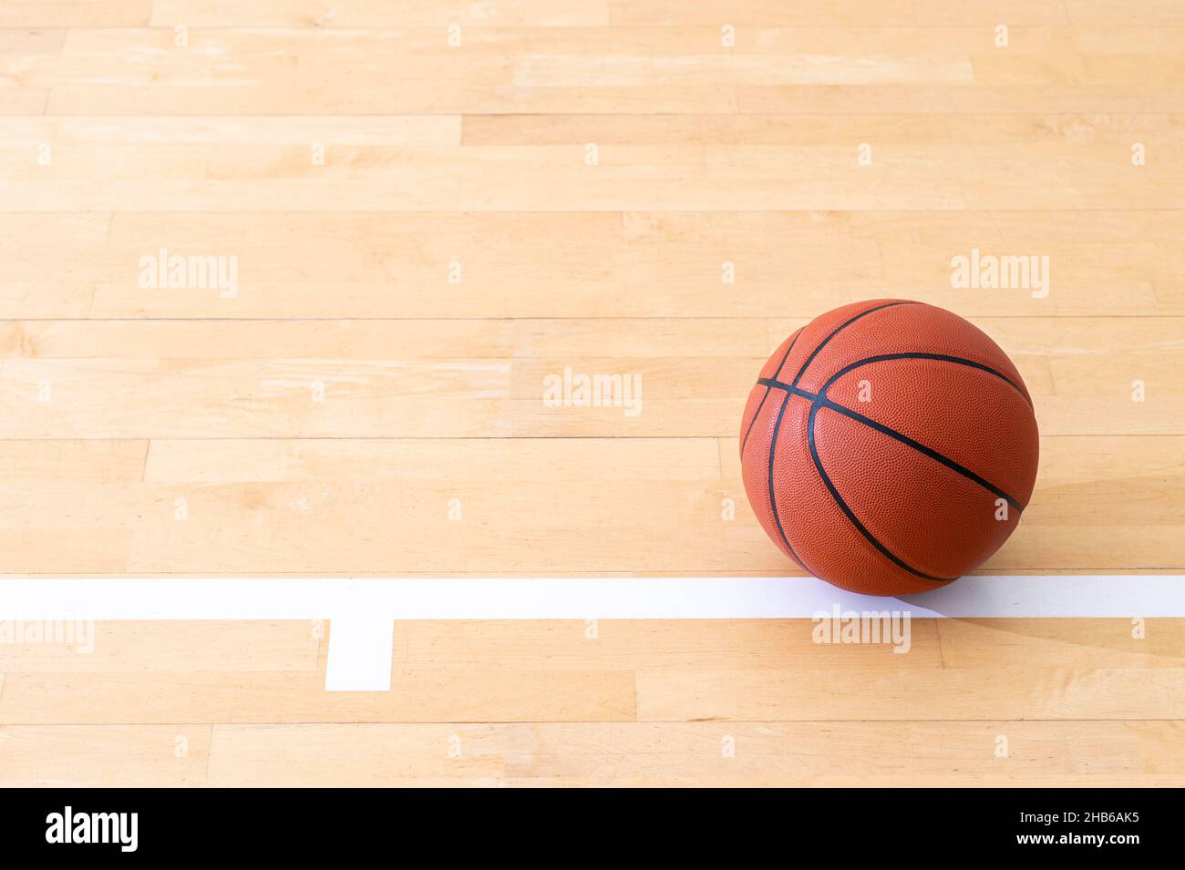 Basketball on hardwood court floor with natural lighting. Workout ...