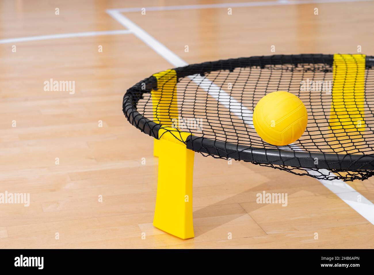 Spike ball game with yellow ball on hardwood court floor. Horizontal ...