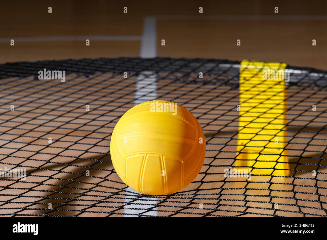 Spike ball game with yellow ball on hardwood court floor. Horizontal ...