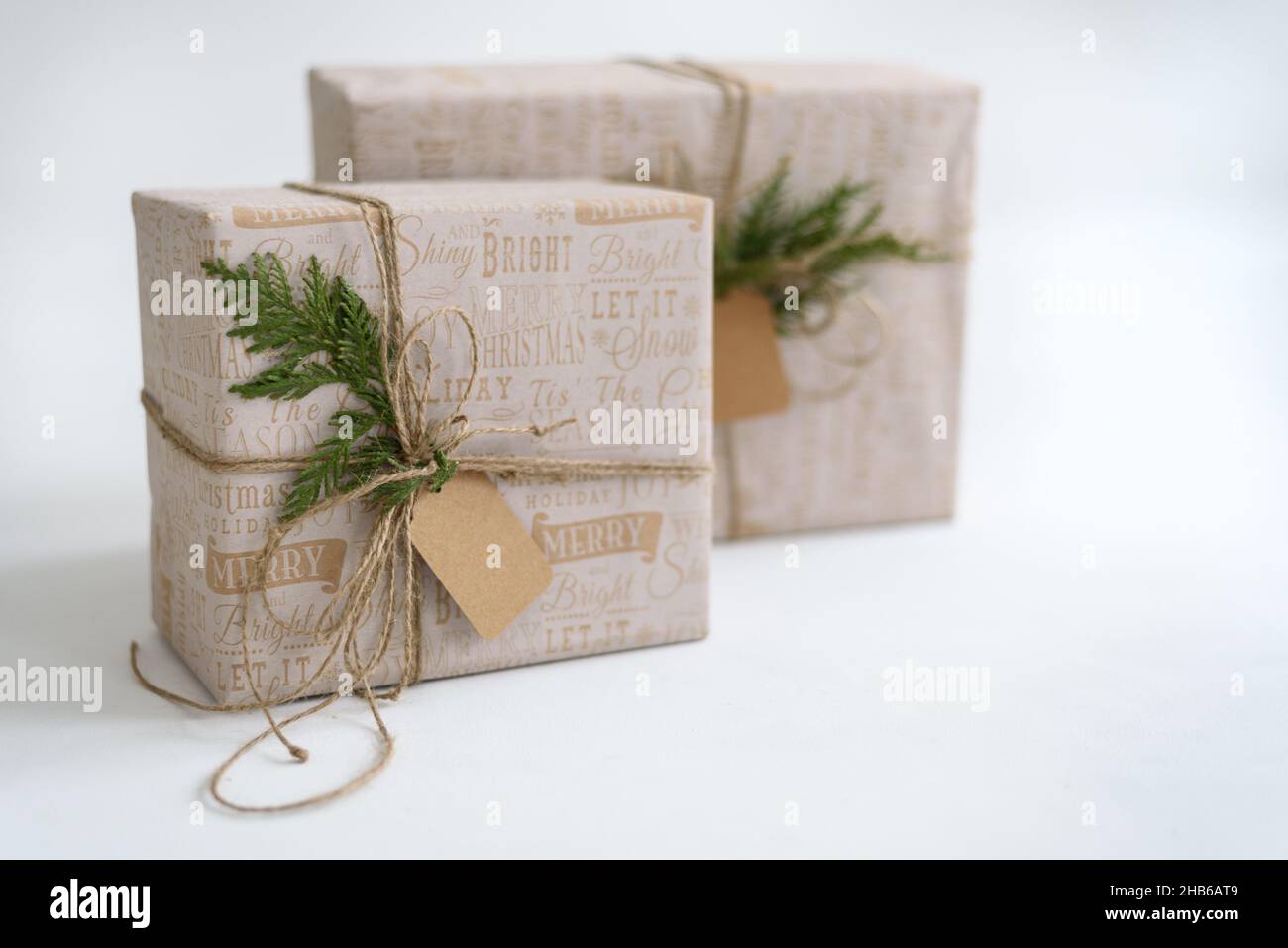 Wrapped in craft paper gift boxes with empty tag on light grey ...