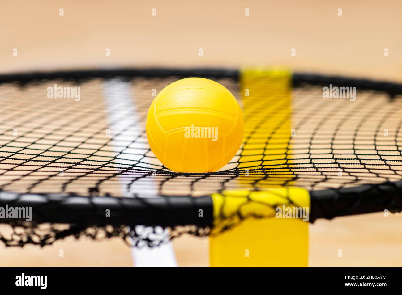 Spike ball game with yellow ball on hardwood court floor. Horizontal ...