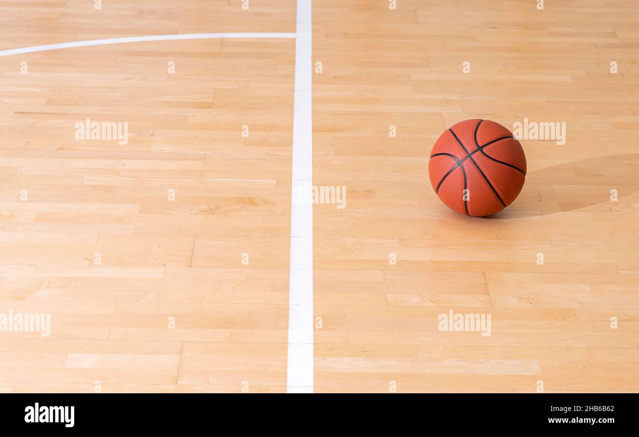 Basketball on hardwood court floor with natural lighting. Workout ...