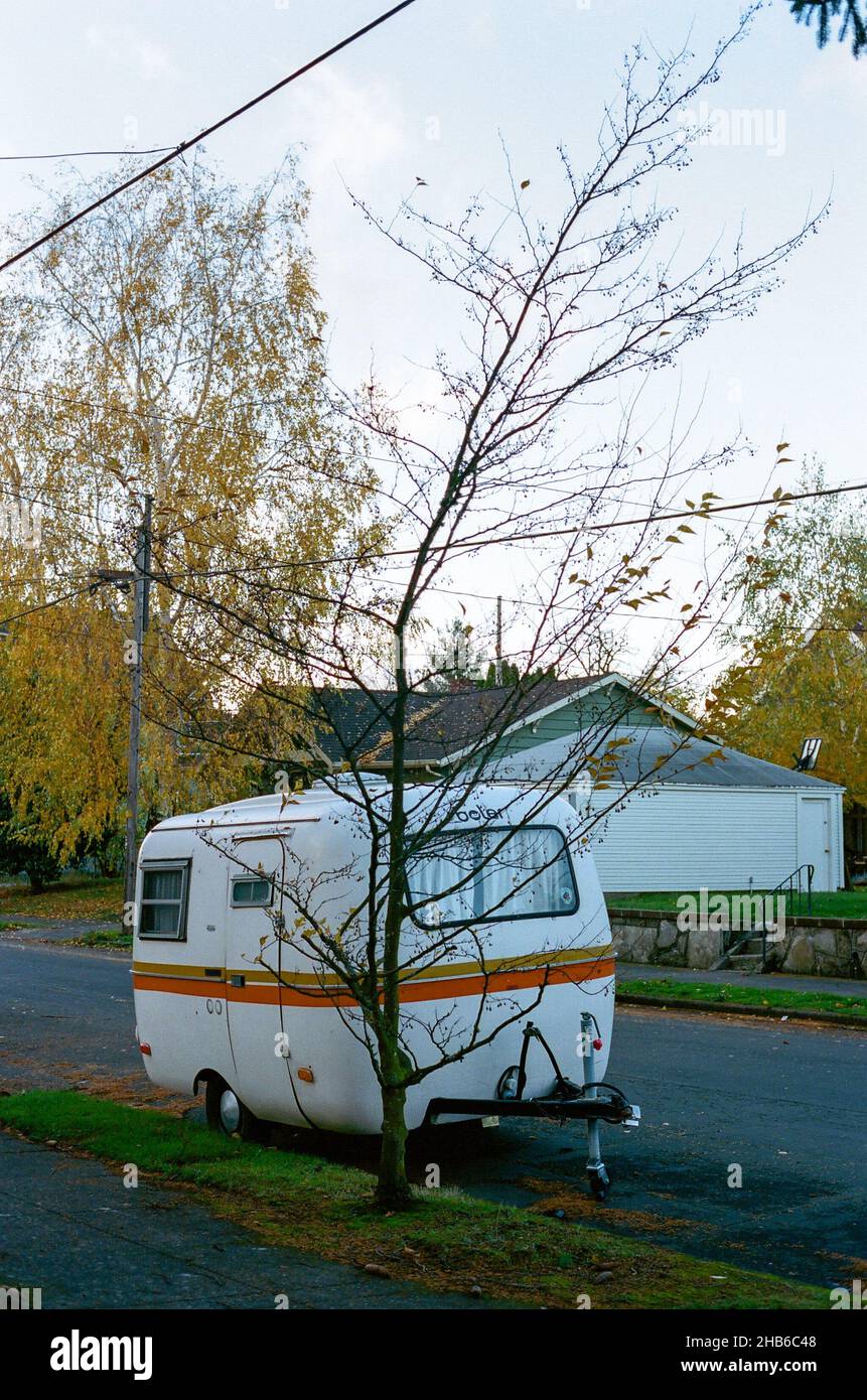 Vertical shot of a small white trailer parked near a house in autumn ...