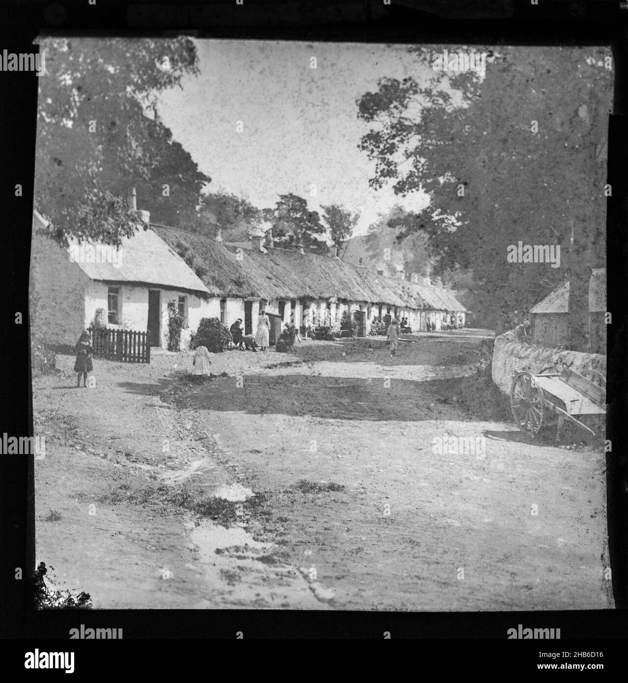 Prosperous looking people sitting outside thatched workers' one storey ...