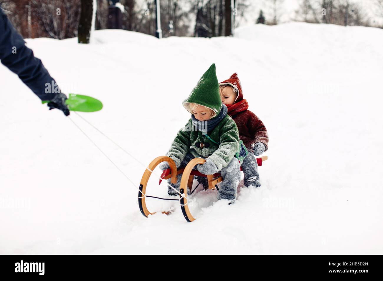 Hand pulling a sled with two cute Caucasian kids in a snowy winter ...