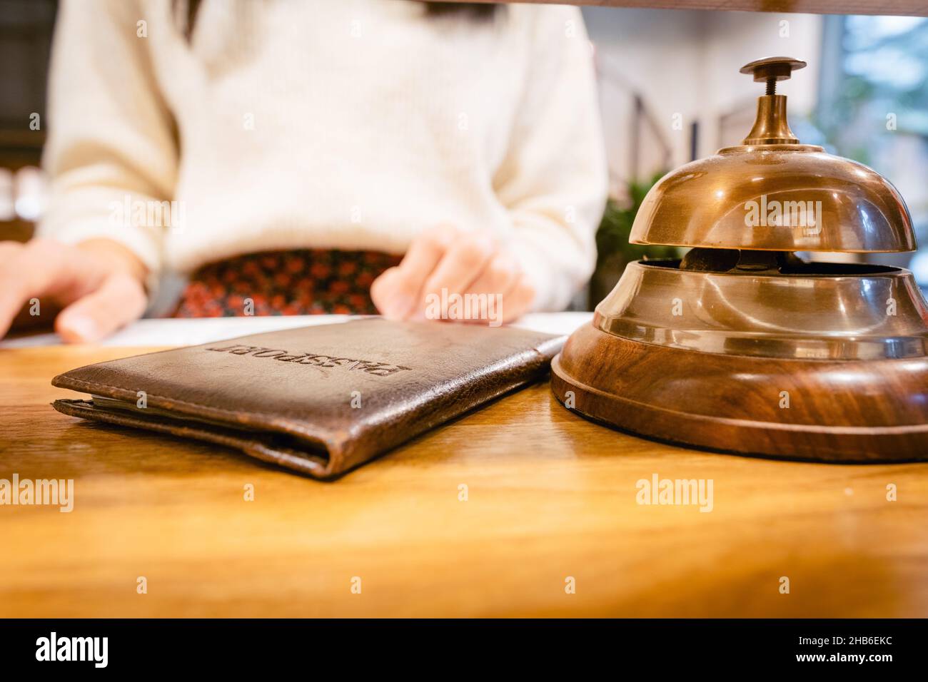 Giant hotel bell ring standing on wooden check in tablewith person ...