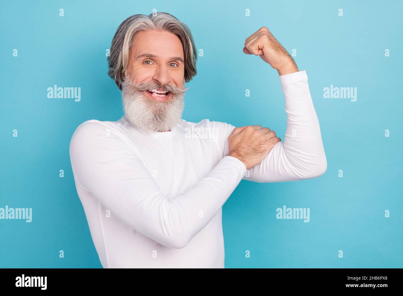 Portrait of attractive cheerful strong grey-haired man touching biceps ...