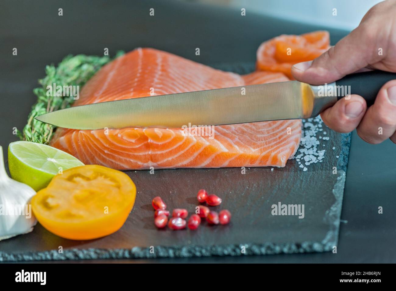 Hand chef using knife slice raw salmon on chopping block. Salmon fillet ...