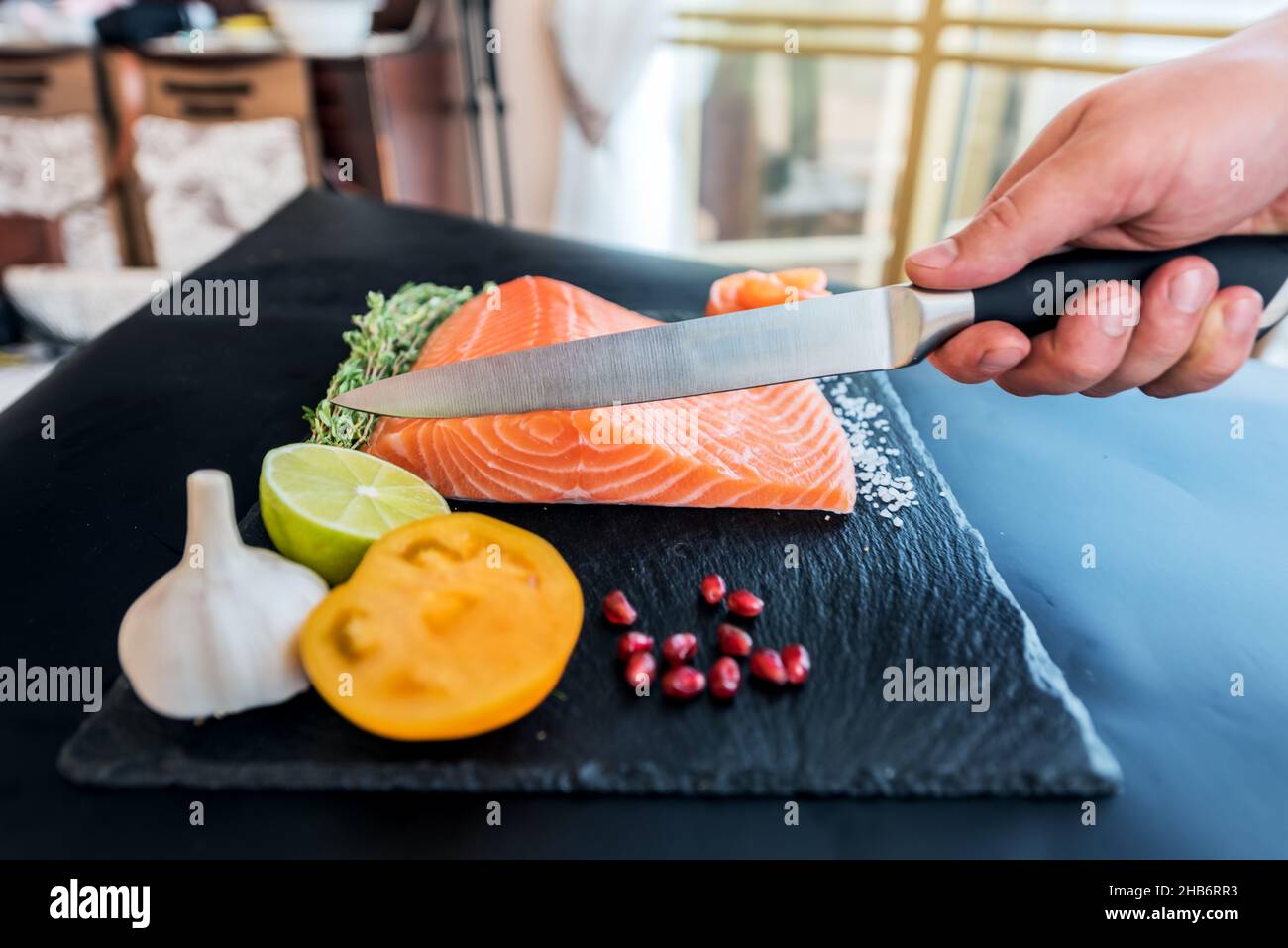 Hand chef using knife slice raw salmon on chopping block. Salmon fillet ...