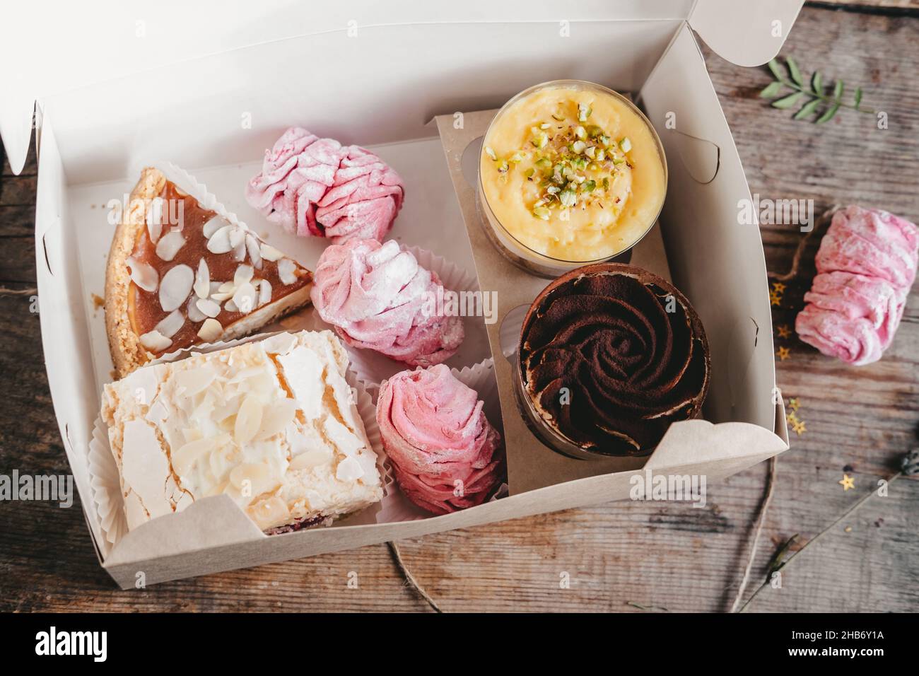 open box with different cakes and marshmallows, on a wooden background ...