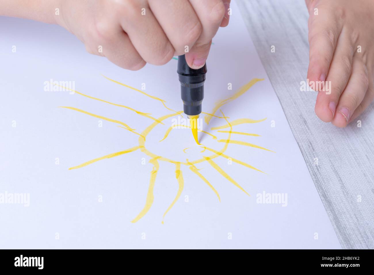 Children's hands are drawing with a felt-tip pen, a pen a happy yellow ...