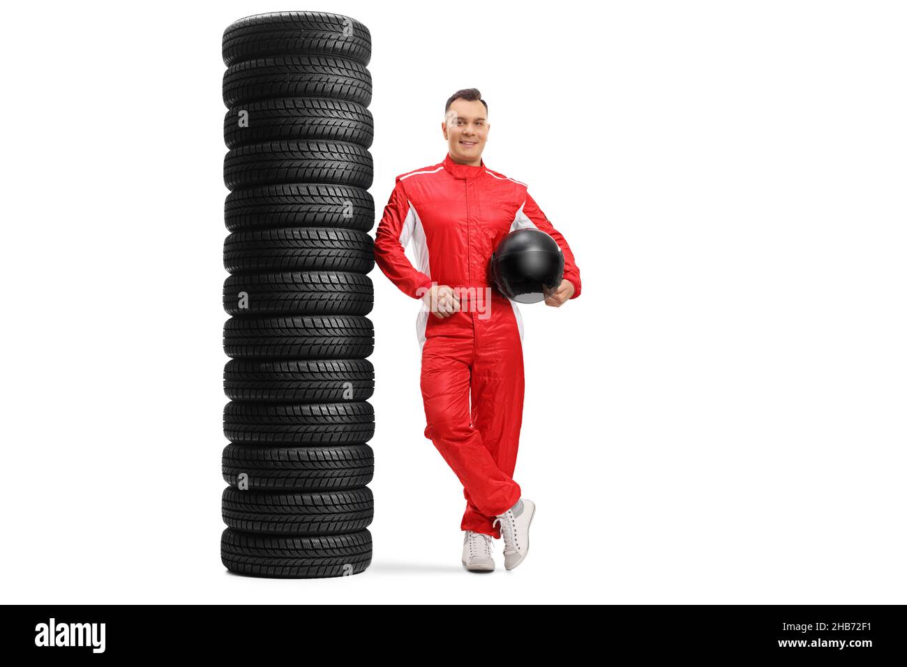 Full length portrait of a racer leaning on a pile of tires and holding ...