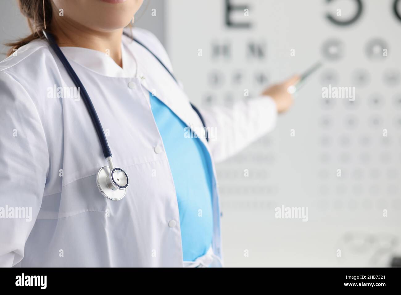 Female eye doctor point on letter on eye test chart Stock Photo - Alamy