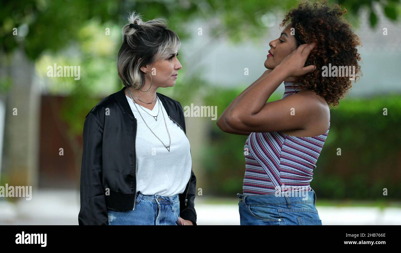 Two diverse friends talking outside at park. people conversation Stock ...