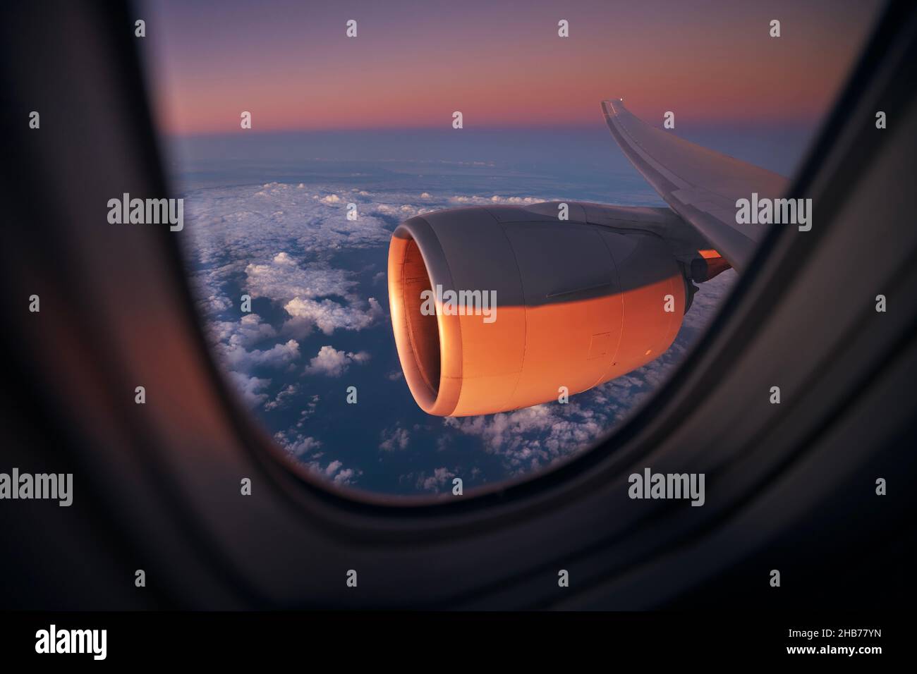 View from window of airplane during flight above ocean at beautiful sunrise. Selective focus on ...