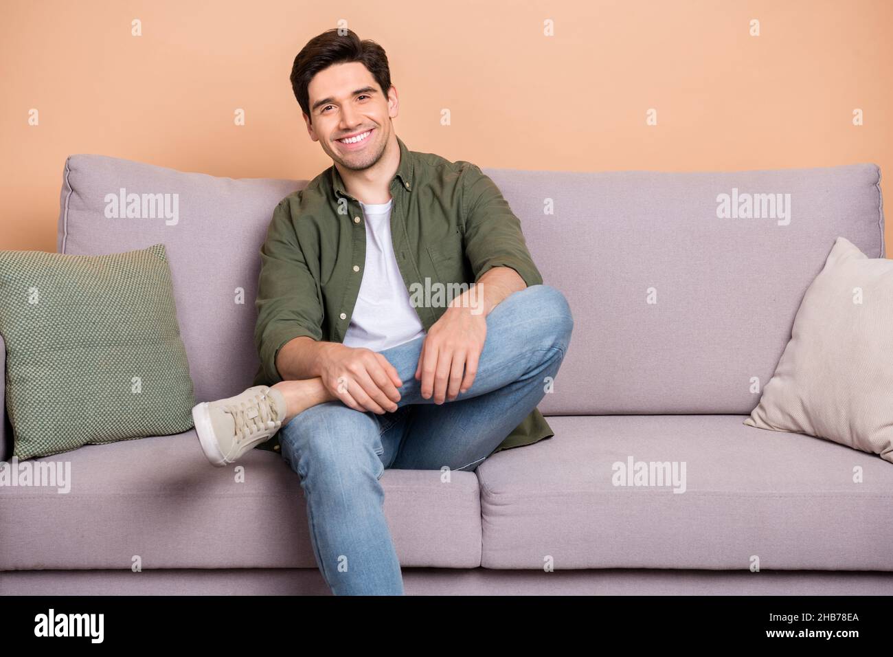 Photo of positive cheerful guy sit comfy divan resting new house ...