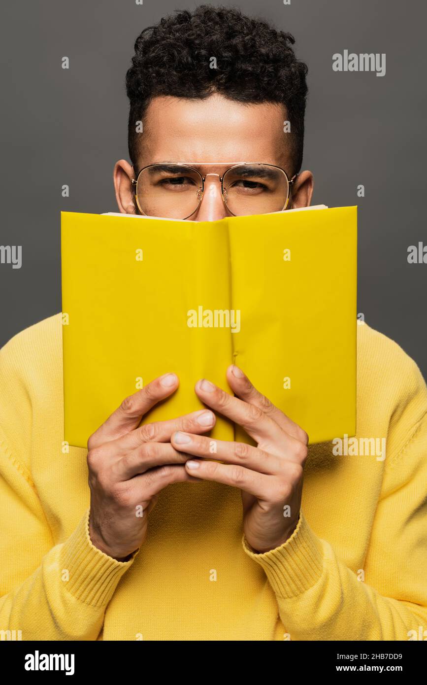 African American Man In Glasses And Yellow Outfit Holding Book Isolated