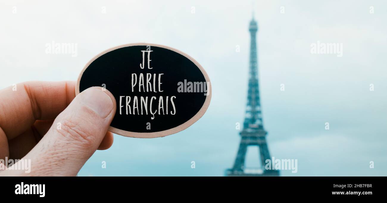 closeup of a man holding a black signboard with the text I speak French ...