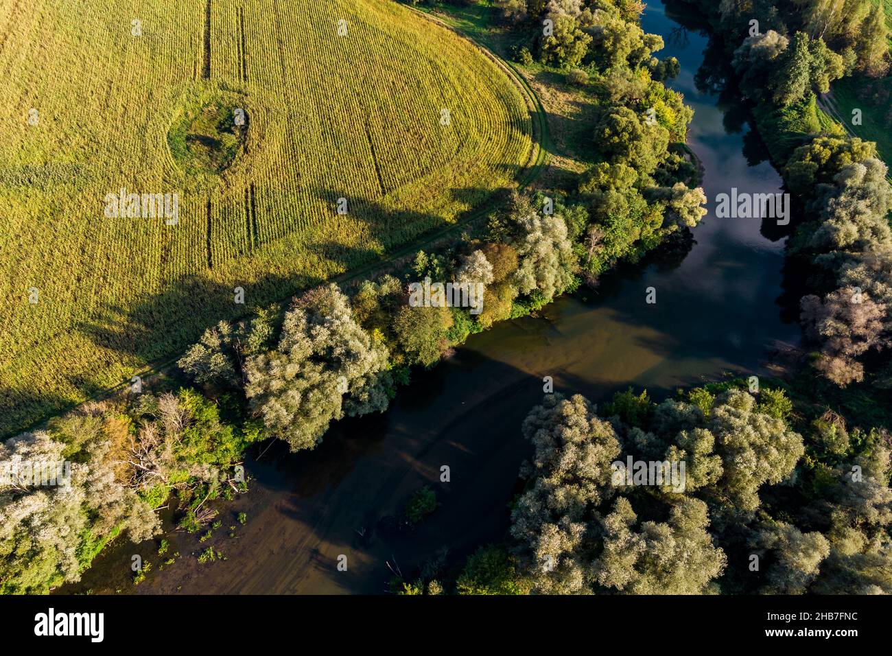 Bird's-eye view of a bend in a river flowing through agricultural ...