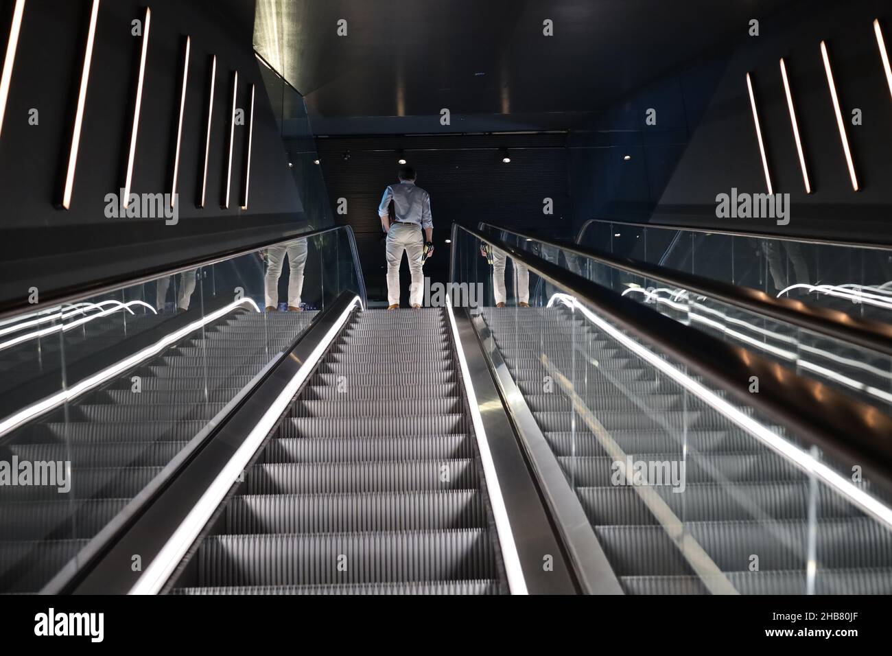 Back view of a male on an illuminated escalator Stock Photo - Alamy