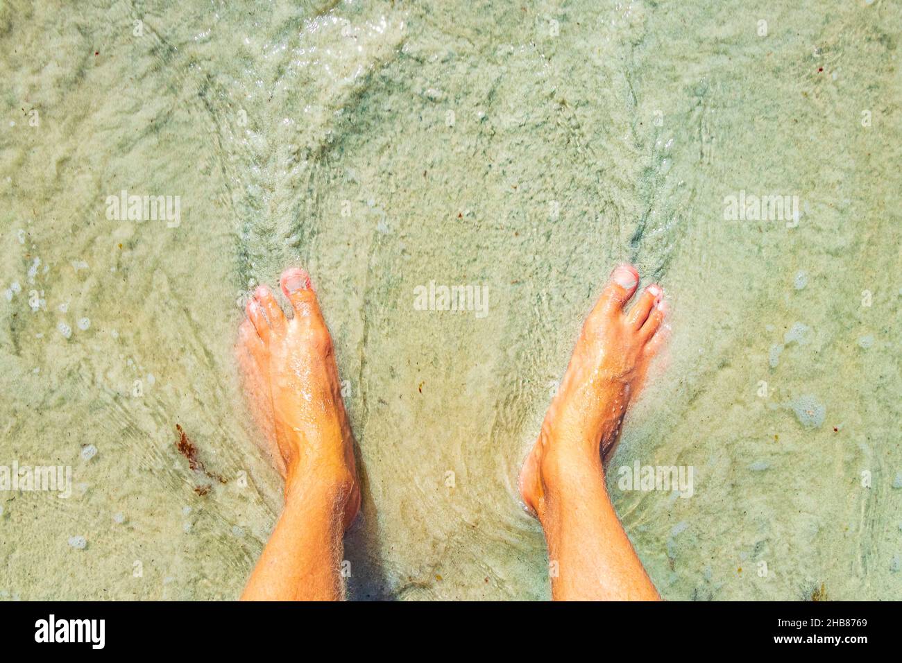 Feet in the water and sand of the tropical mexican beach of Playa 88 ...