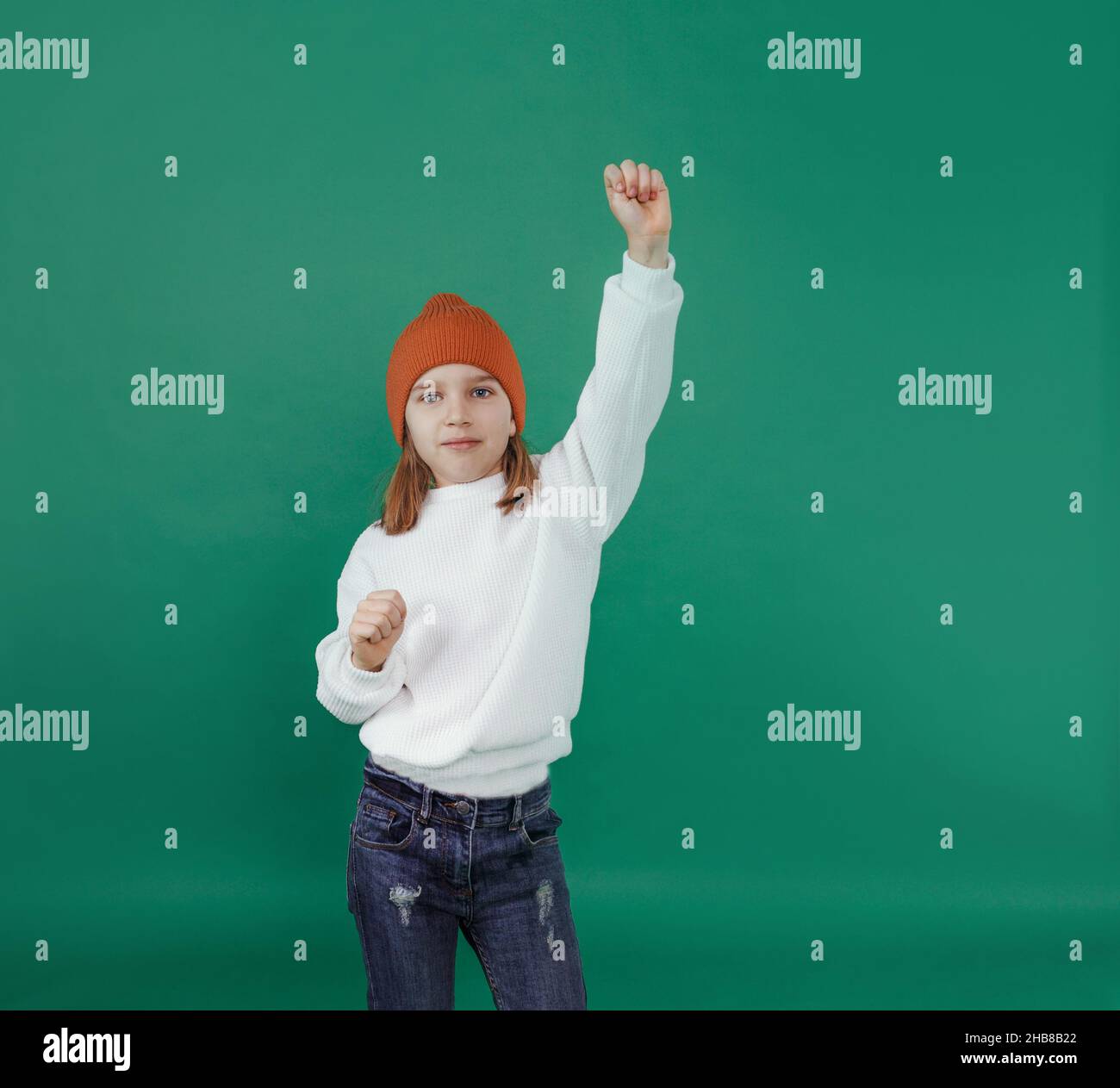 The boy is happy. He is wearing a white sweater and jeans. He raised his right hand up. children ...