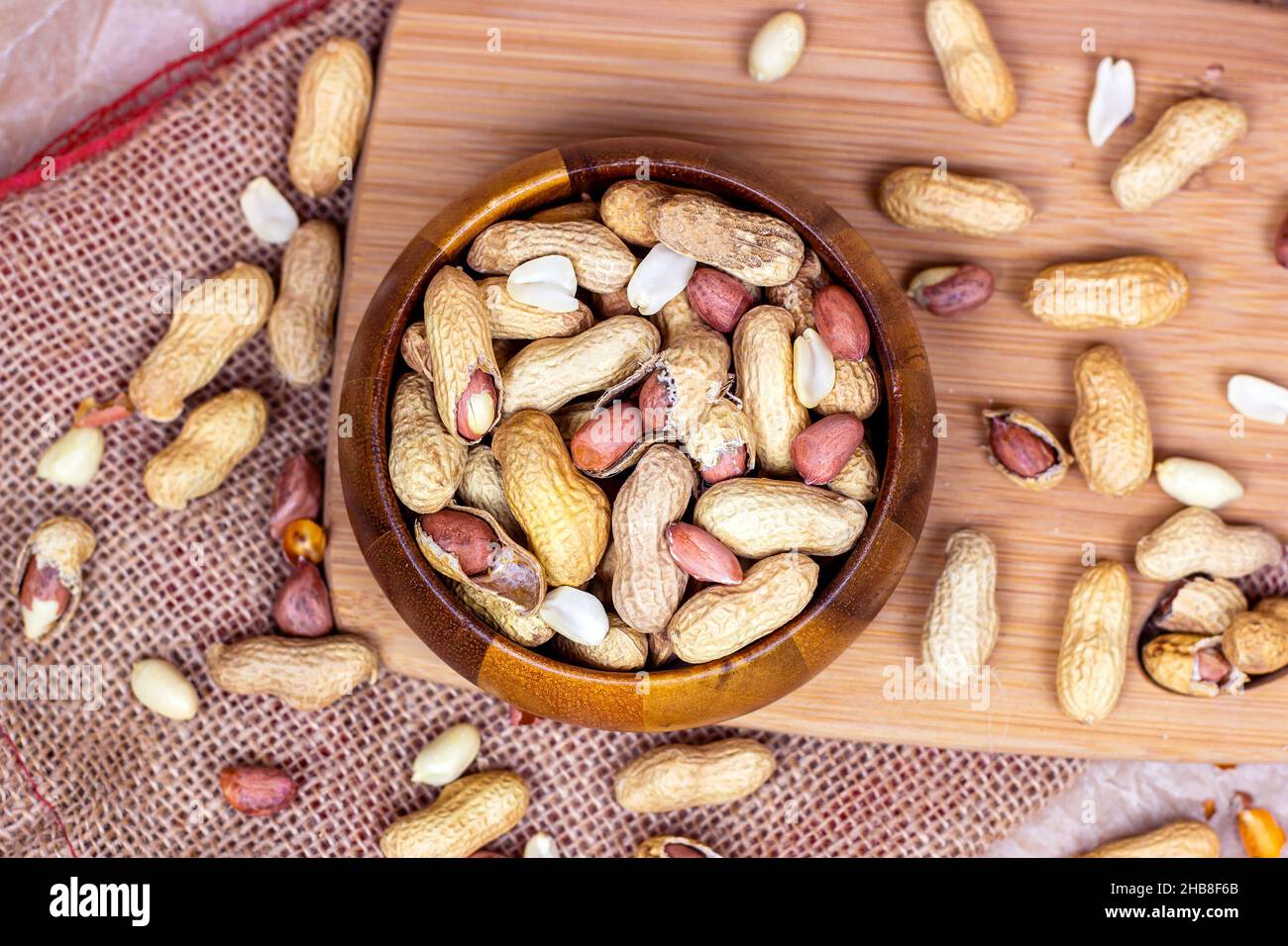 Top view of raw unpeeled peanut nuts in nutshell in brown round wooden ...
