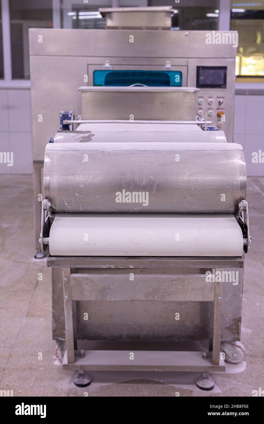 Baker making dough for pastry on dough sheeter. Dough rolling machine ...