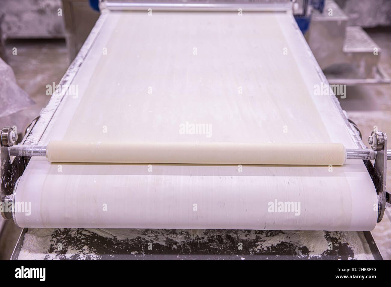 Baker making dough for pastry on dough sheeter. Dough rolling machine ...