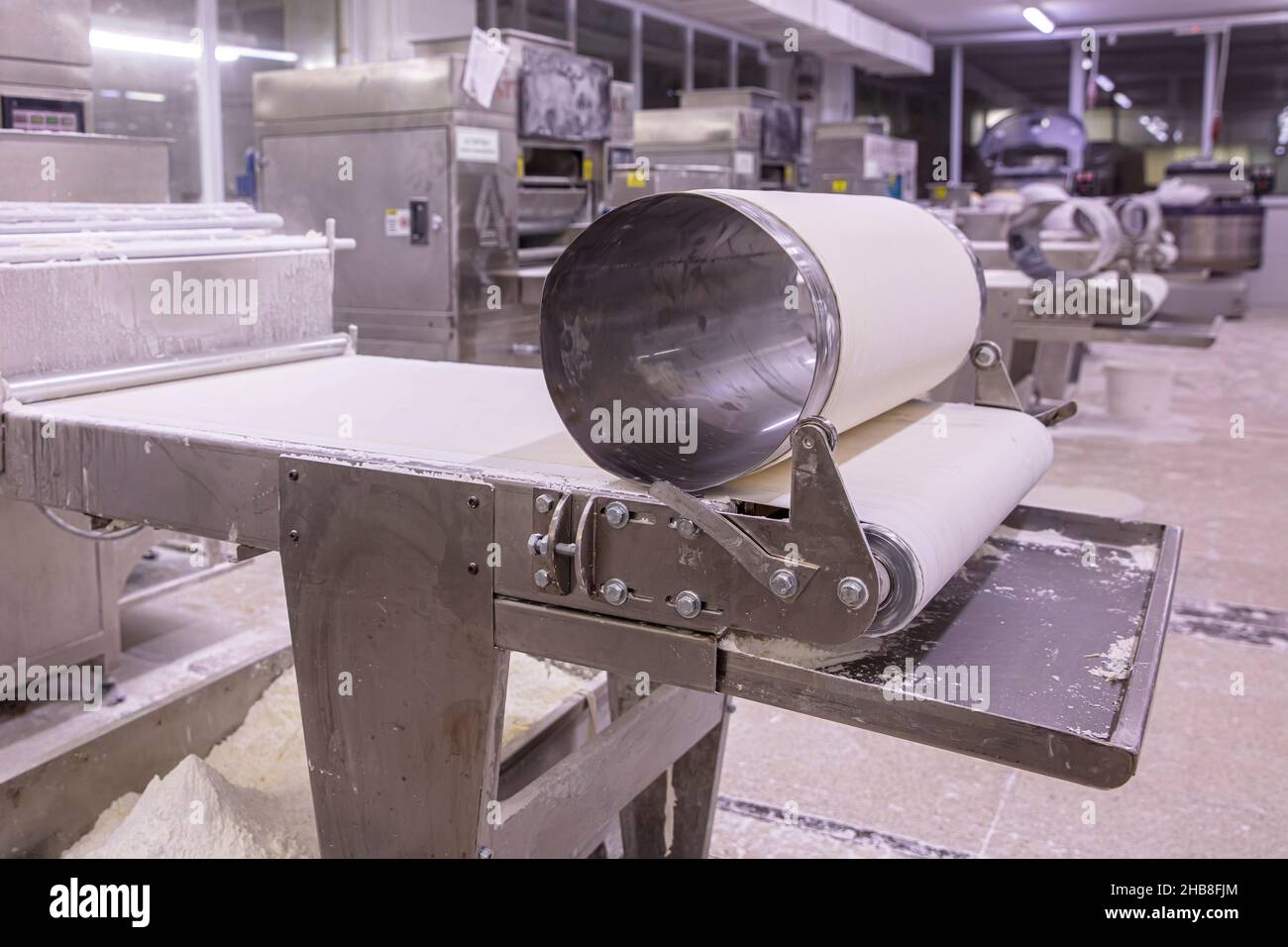 Baker making dough for pastry on dough sheeter. Dough rolling machine ...