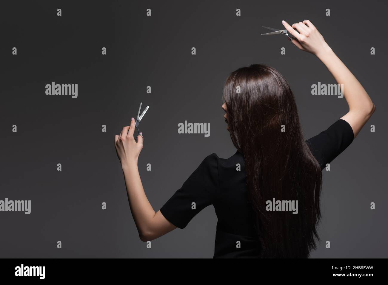 back view of woman with long shiny hair holding scissors isolated on ...
