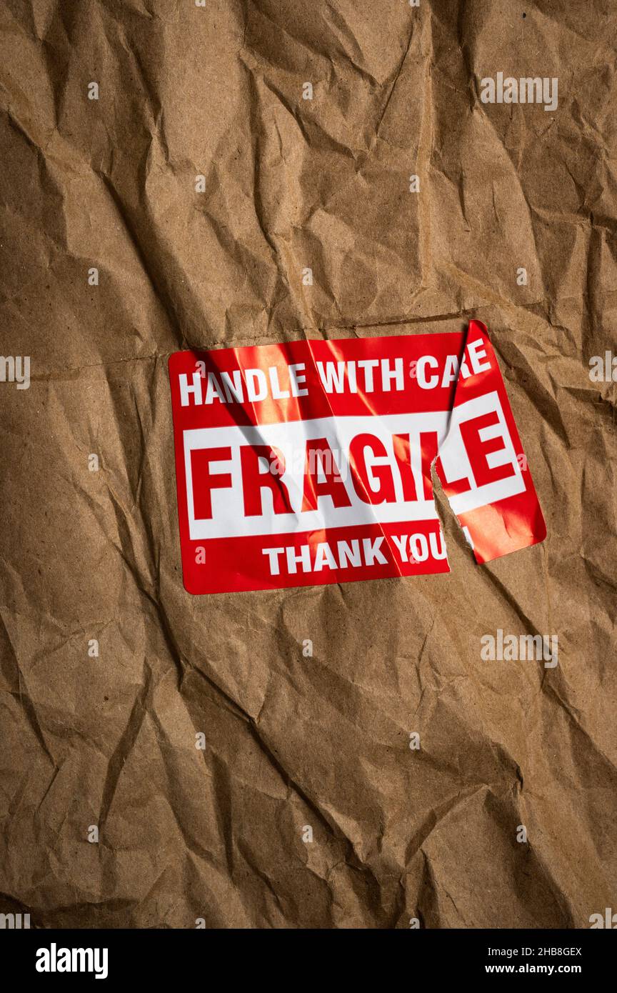Fragile handle with care sticker on crushed package Stock Photo - Alamy
