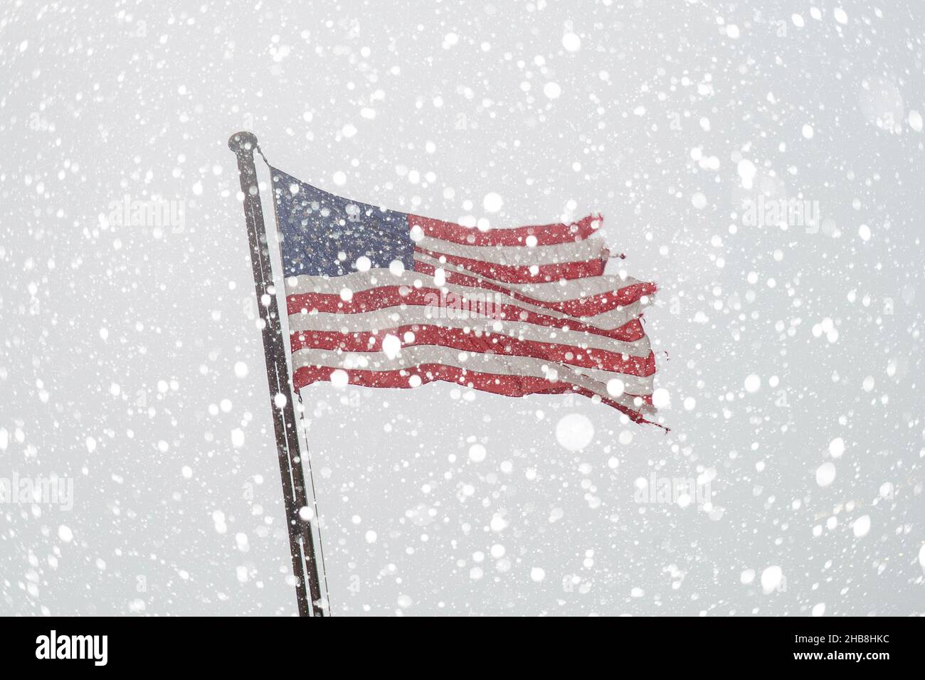 Torn American flag on flag pole with falling snow Stock Photo - Alamy