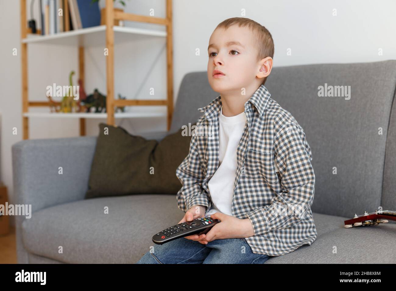 Kid holding TV remote controller. Boy without parental control watching ...