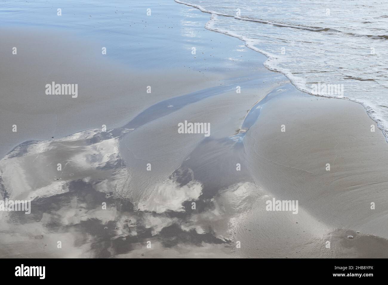 wet sand and reflection of clouds on the Mediterranean beach relaxing ...