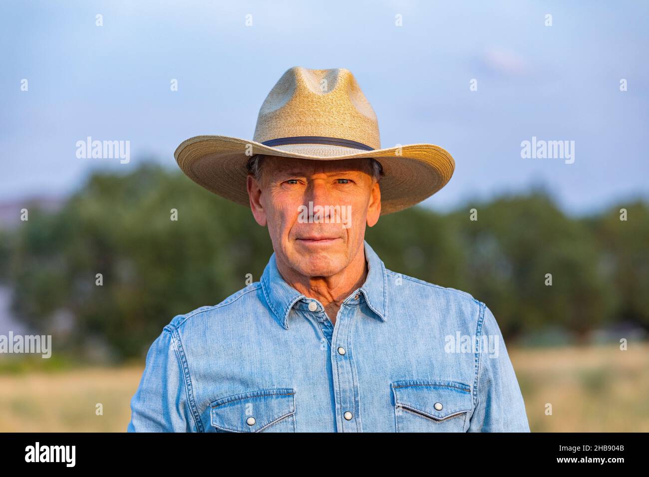 Portrait of senior man in denim shirt and cowboy hat Stock Photo - Alamy