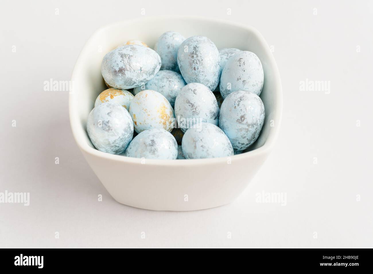 Blue chocolate coated Easter eggs candies on a bowl isolated on a white ...