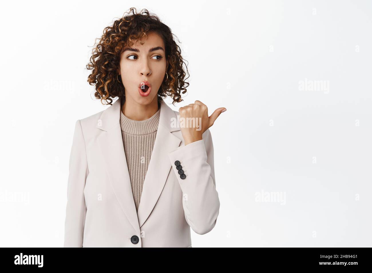 Surprised stylish corporate woman in suit, pointing and looking at ...