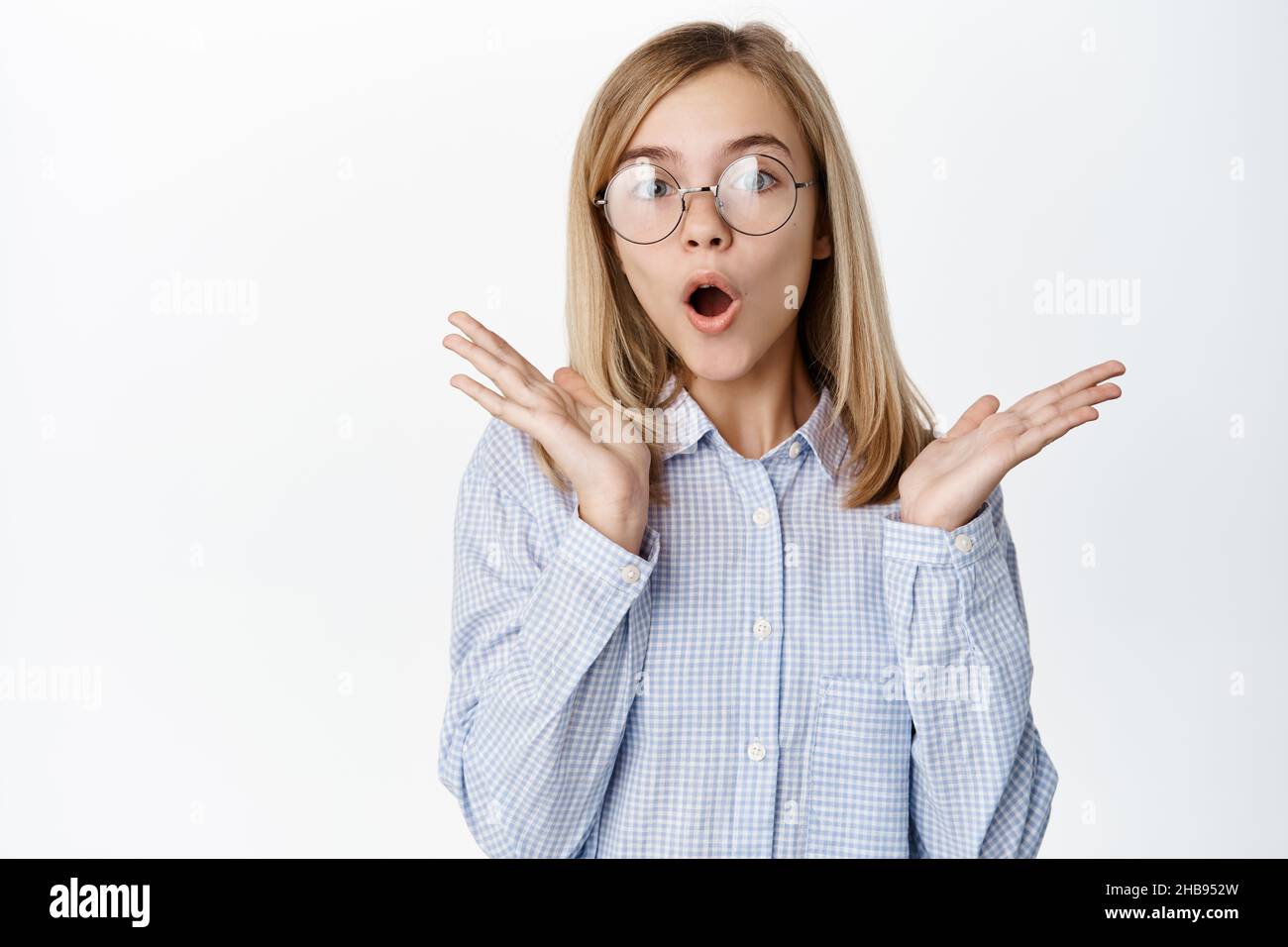 Surprised small girl, teenager in glasses looking amazed, standing over ...