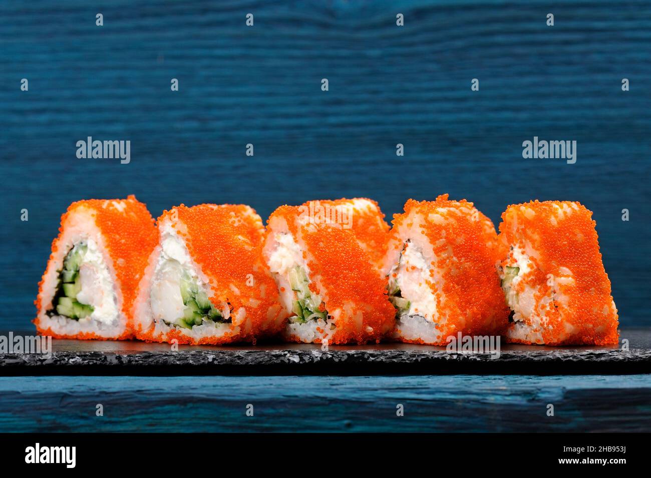 Triangular vegetarian rolls with cucumber, cream cheese and orange roe ...