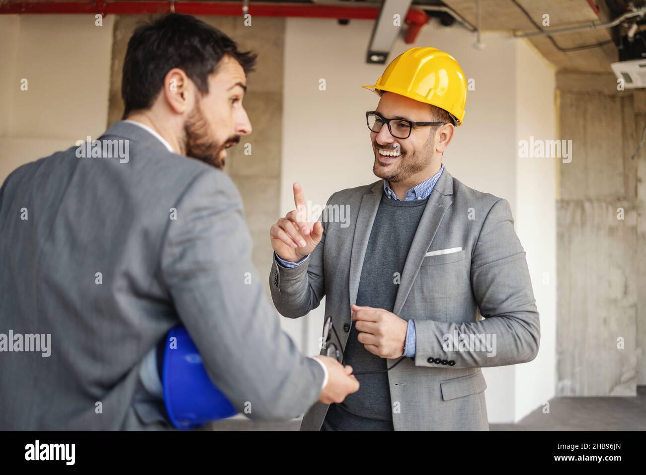 Smiling architect talking to investor while standing in building in ...