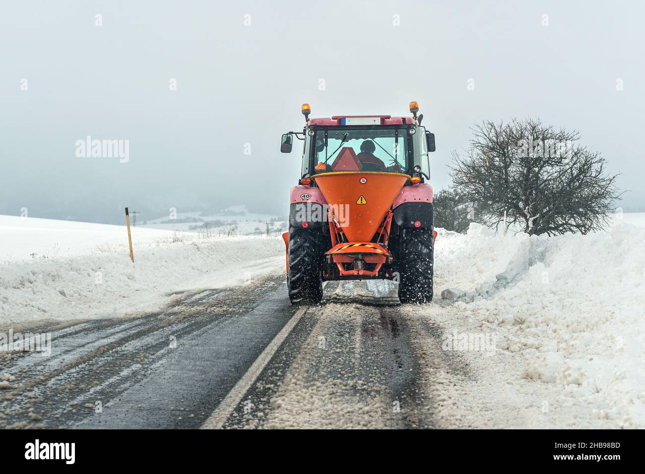 Small gritter maintenance tractor spreading de icing salt on asphalt ...
