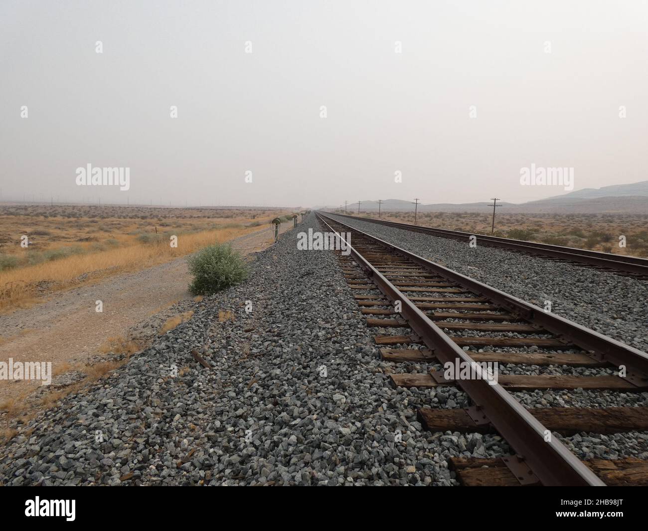 Endless train track in the desert against a hazy sky Stock Photo - Alamy