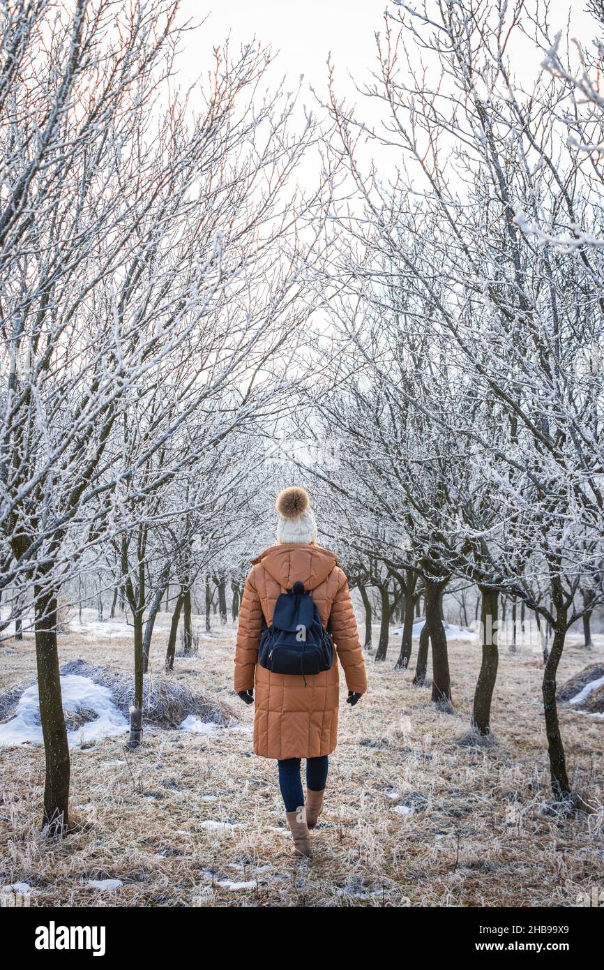 Woman wearing winter clothes and backpack. Female tourist walking at ...