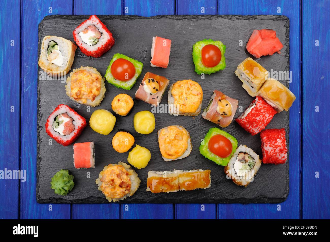 Set of various japanese fusion rolls on black plate flatlay overhead ...