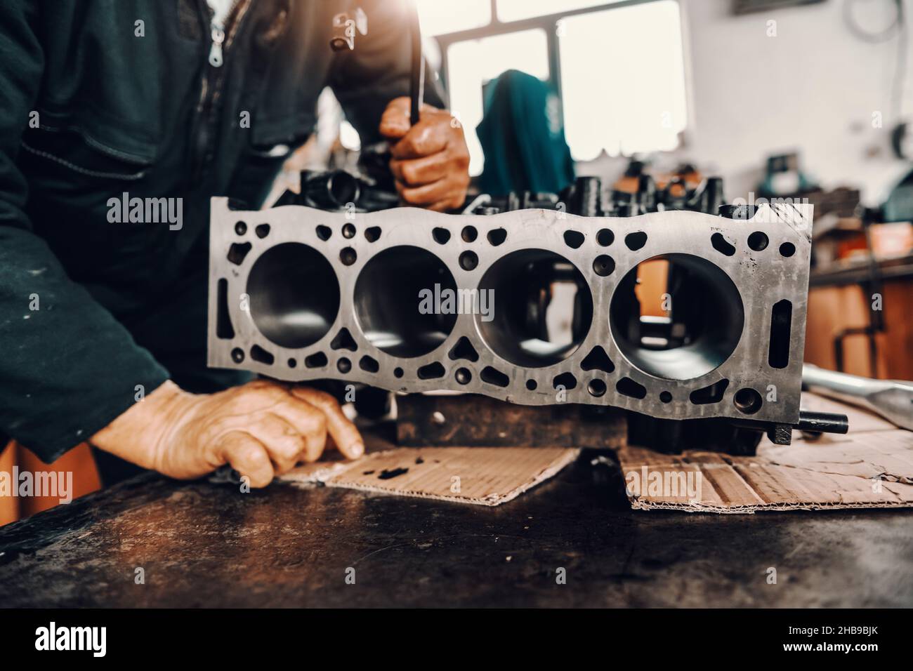 Auto mechanic adjusting cylinder head on engine block at workshop Stock ...