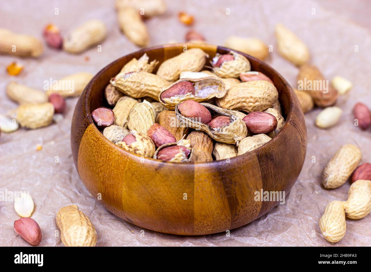 Raw unpeeled peanut nuts in nutshell in brown round wooden bowl on ...